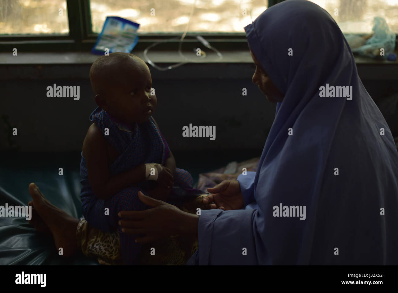 A malnourished child is held by their mother at Banadir Hospital in ...