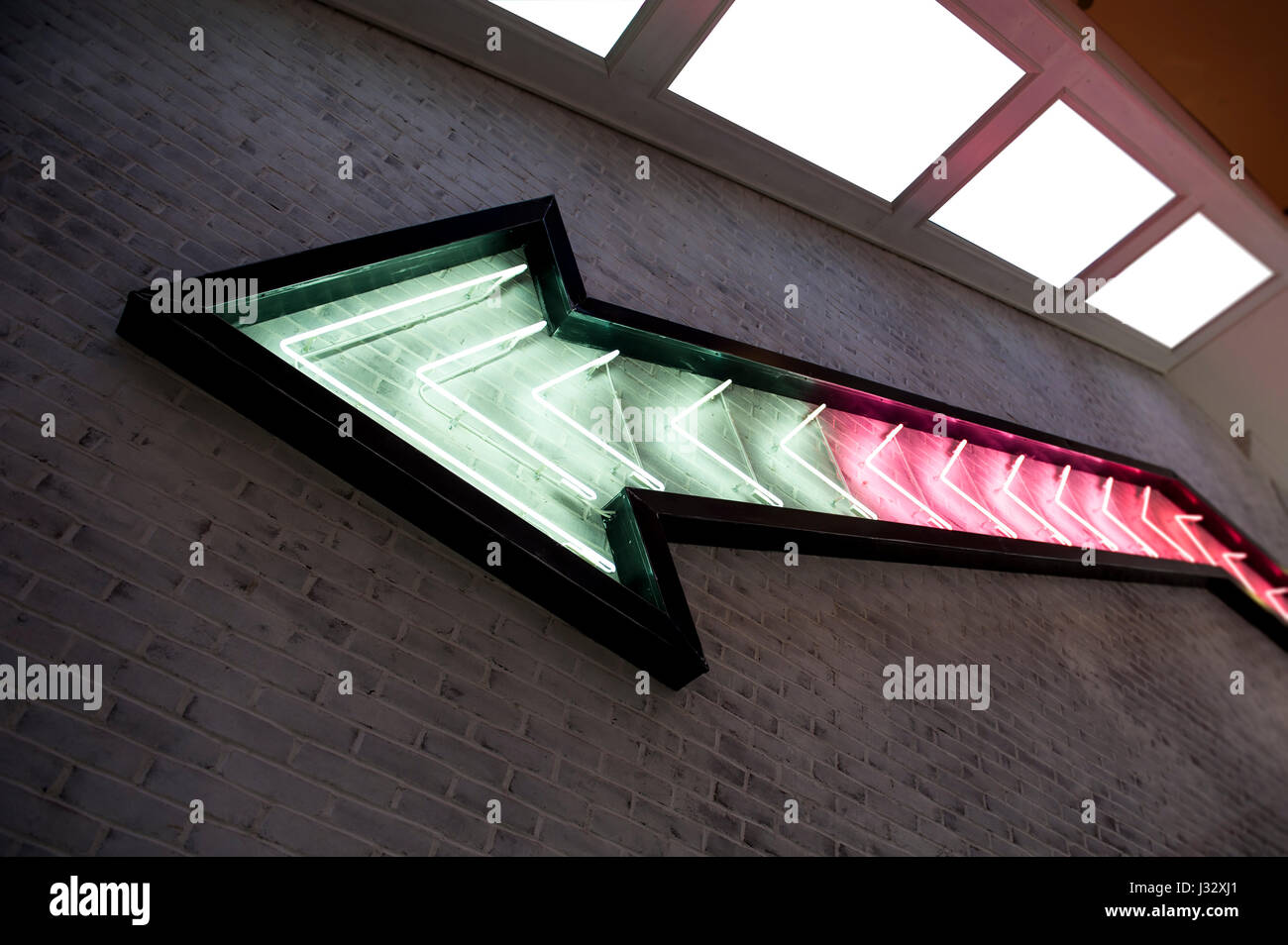 Arrow made of neon on a brick wall Stock Photo - Alamy