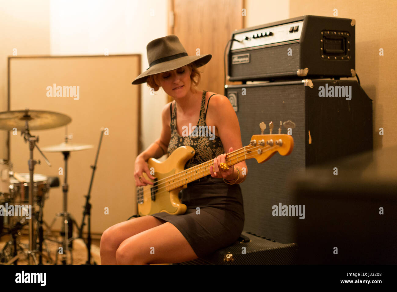 Young female musician playing a bass guitar Stock Photo - Alamy
