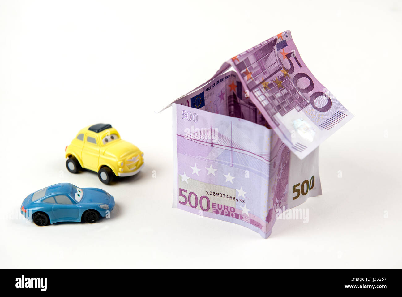 House made with 500 euro banknotes and cars parked outside isolated on ...
