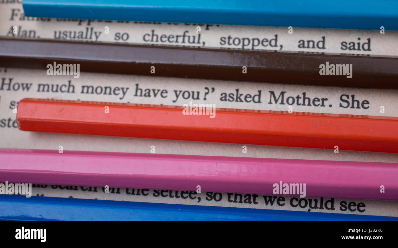 Color pencils placed on the page of a book with text Stock Photo - Alamy