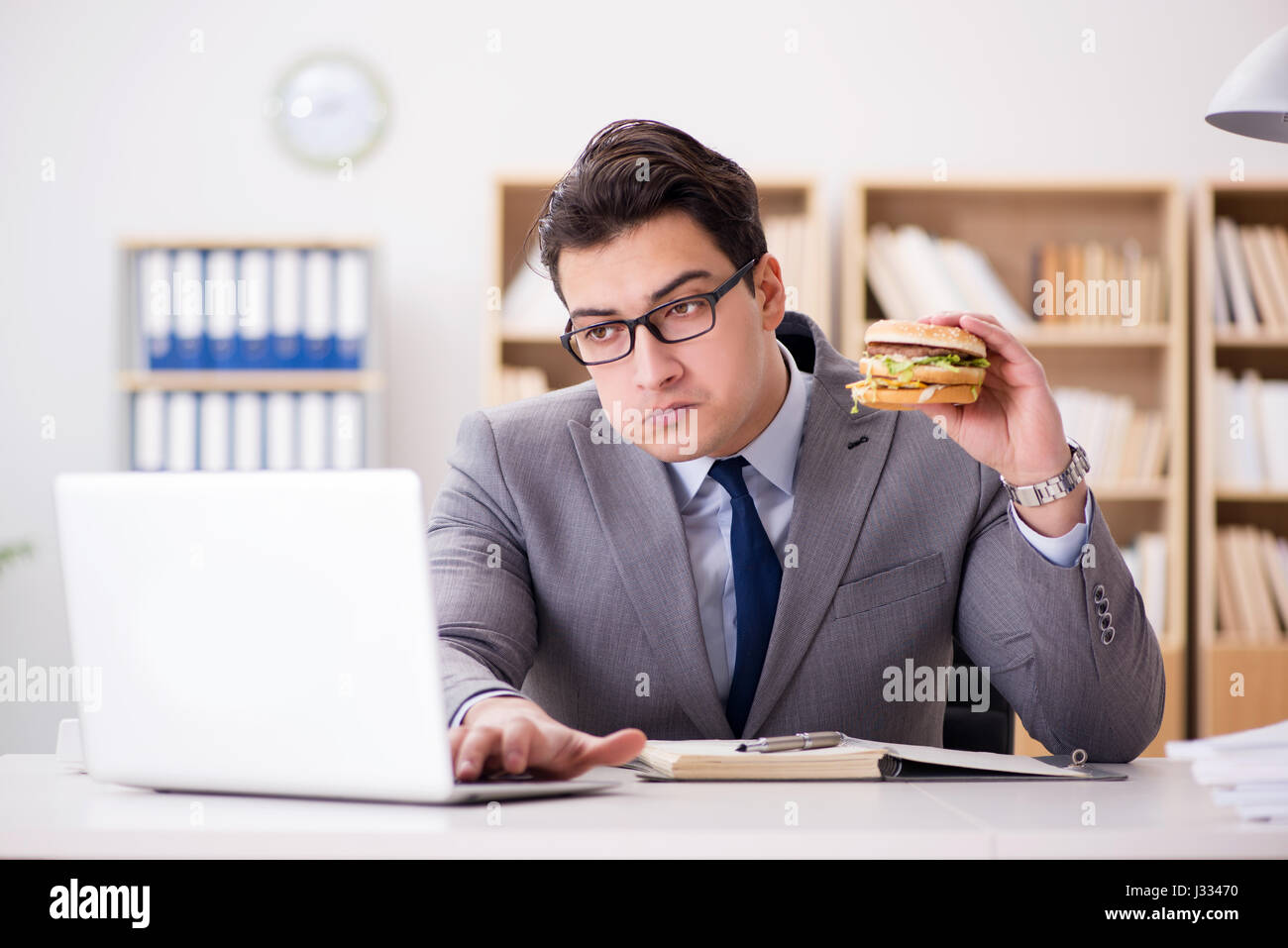 Hungry funny businessman eating junk food sandwich Stock Photo - Alamy