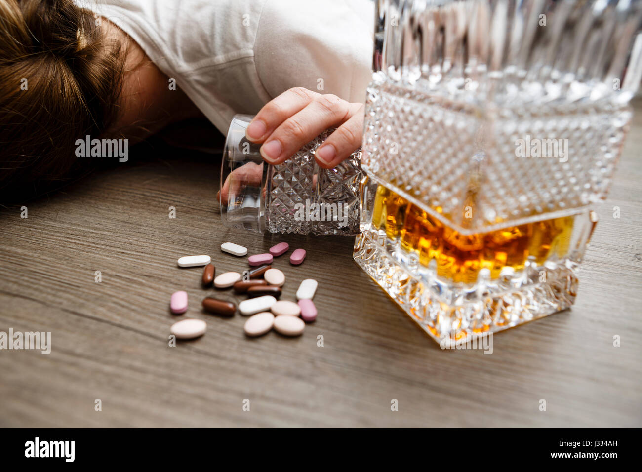 drunk or poisoned young woman with bottle of alcohol and pills, whisky ...