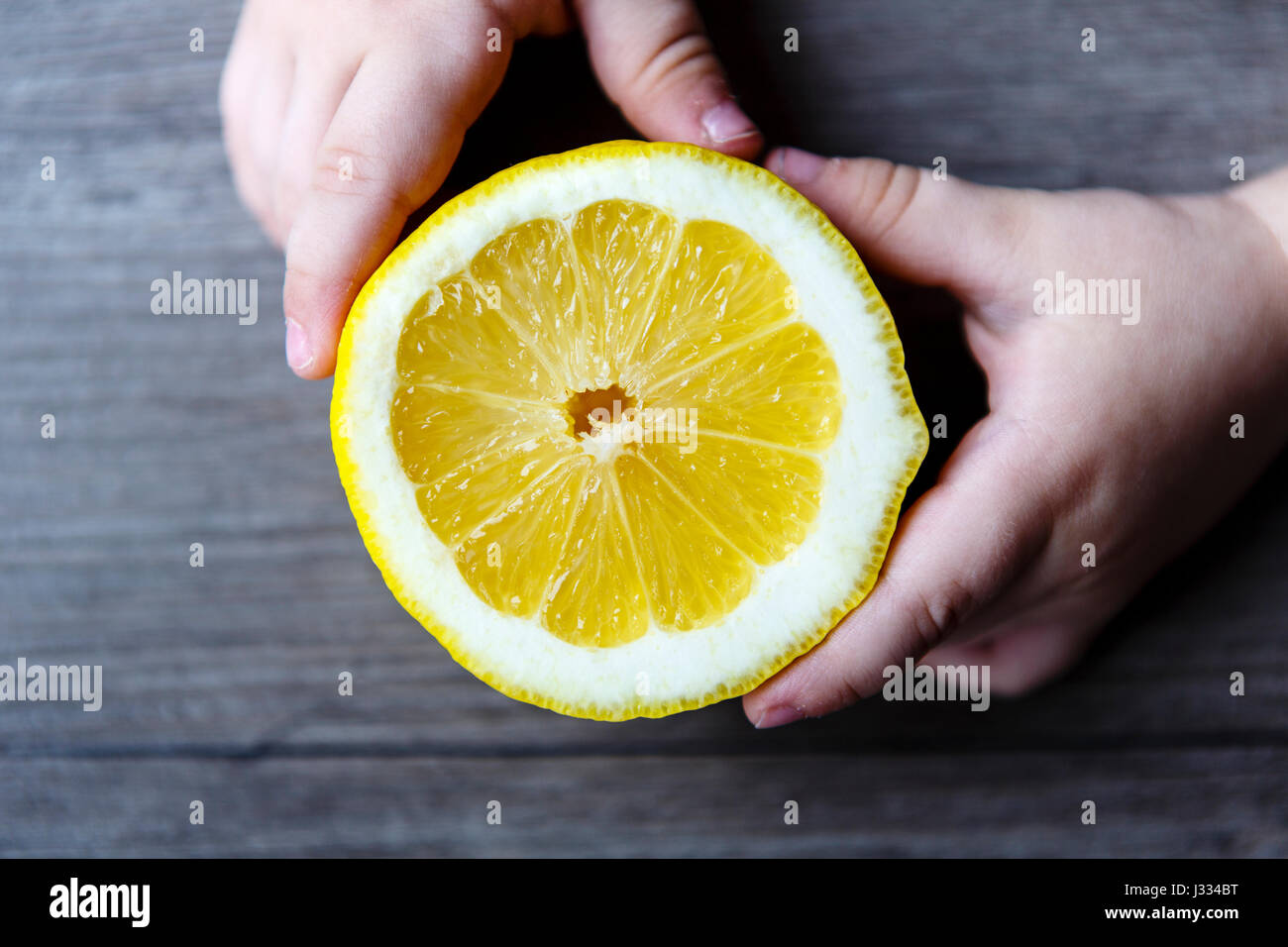 beautiful fresh yellow lemon in little cute kid hands and fingers on ...