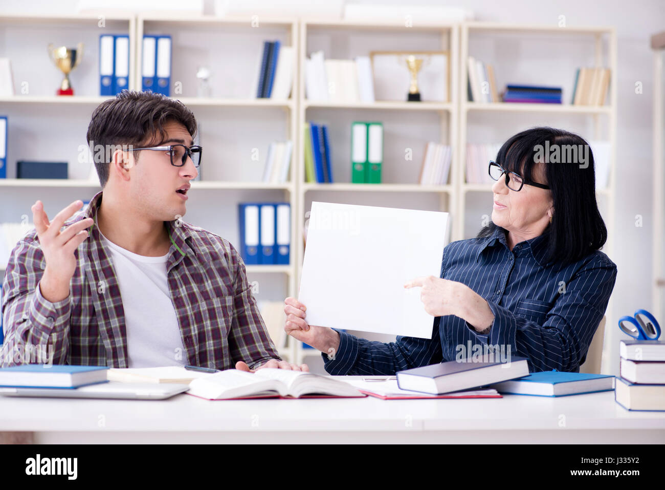 Young student and teacher during tutoring lesson Stock Photo - Alamy