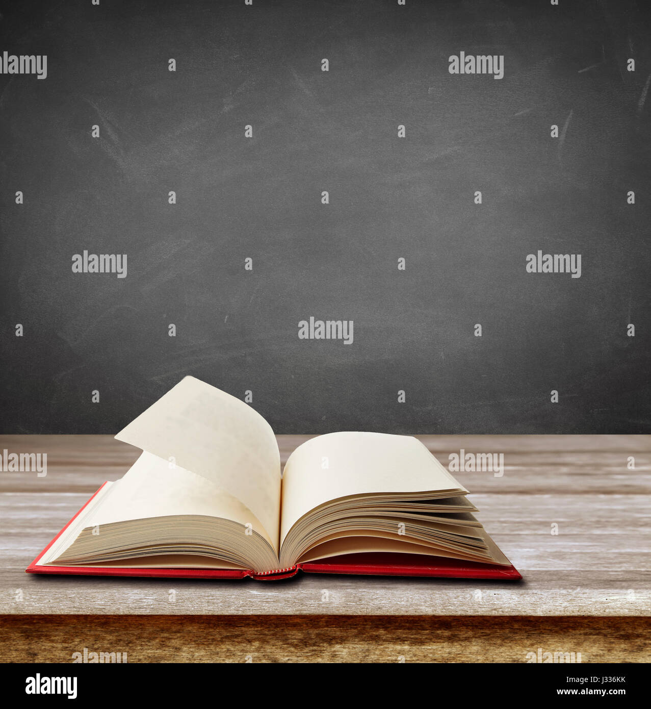 Open book on table in front of grey wall Stock Photo - Alamy