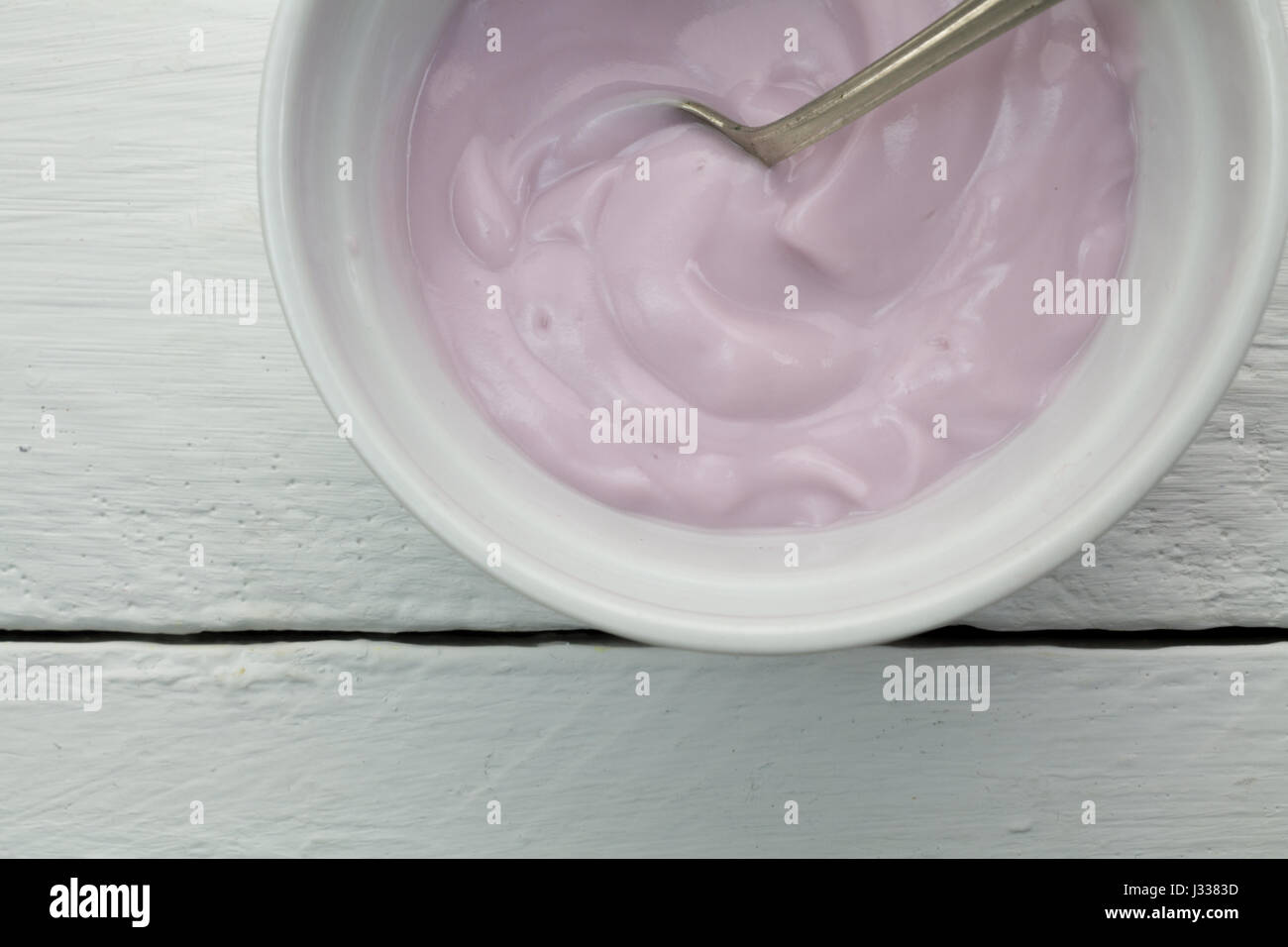 Creamy naturally colored rasberry fruit yogurt in white glass bowl on ...