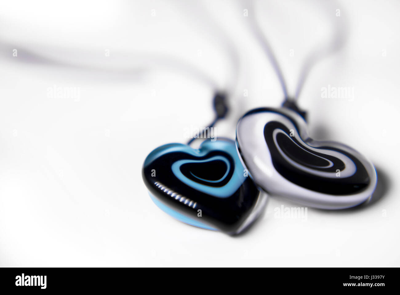 Two glass hearts of black, white and turquoise glass with reflection of ...