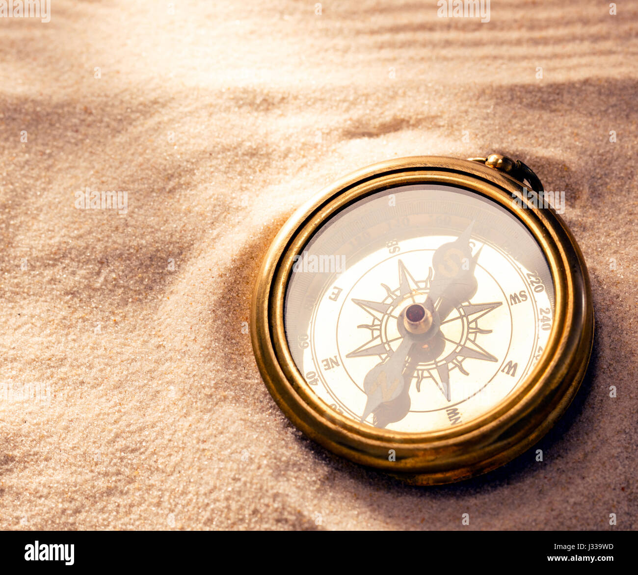 Golden compass with beach sand in closeup Stock Photo - Alamy