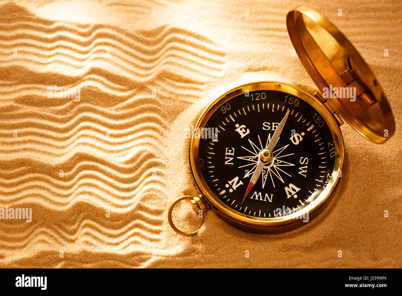 Golden compass with beach sand in closeup Stock Photo - Alamy