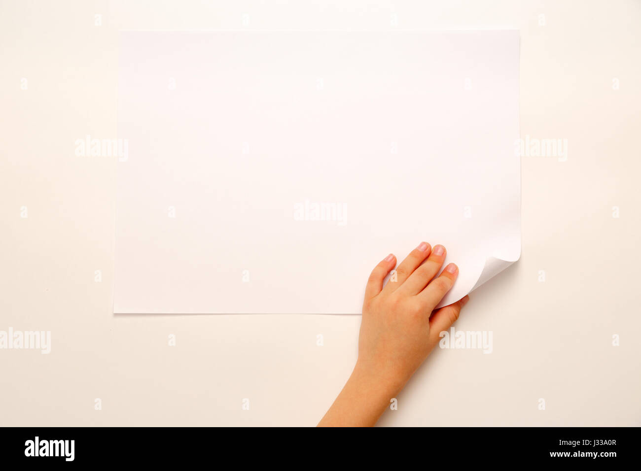 Child's hand turning over sheet of paper Stock Photo - Alamy