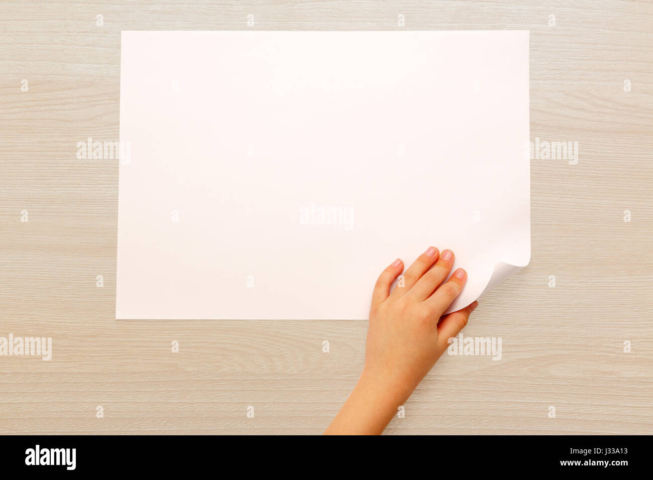 Child's hand turning over sheet of paper Stock Photo - Alamy
