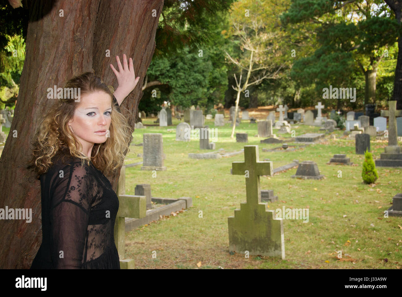 Beautiful blonde girl wearing a black dress in a graveyard Stock Photo ...