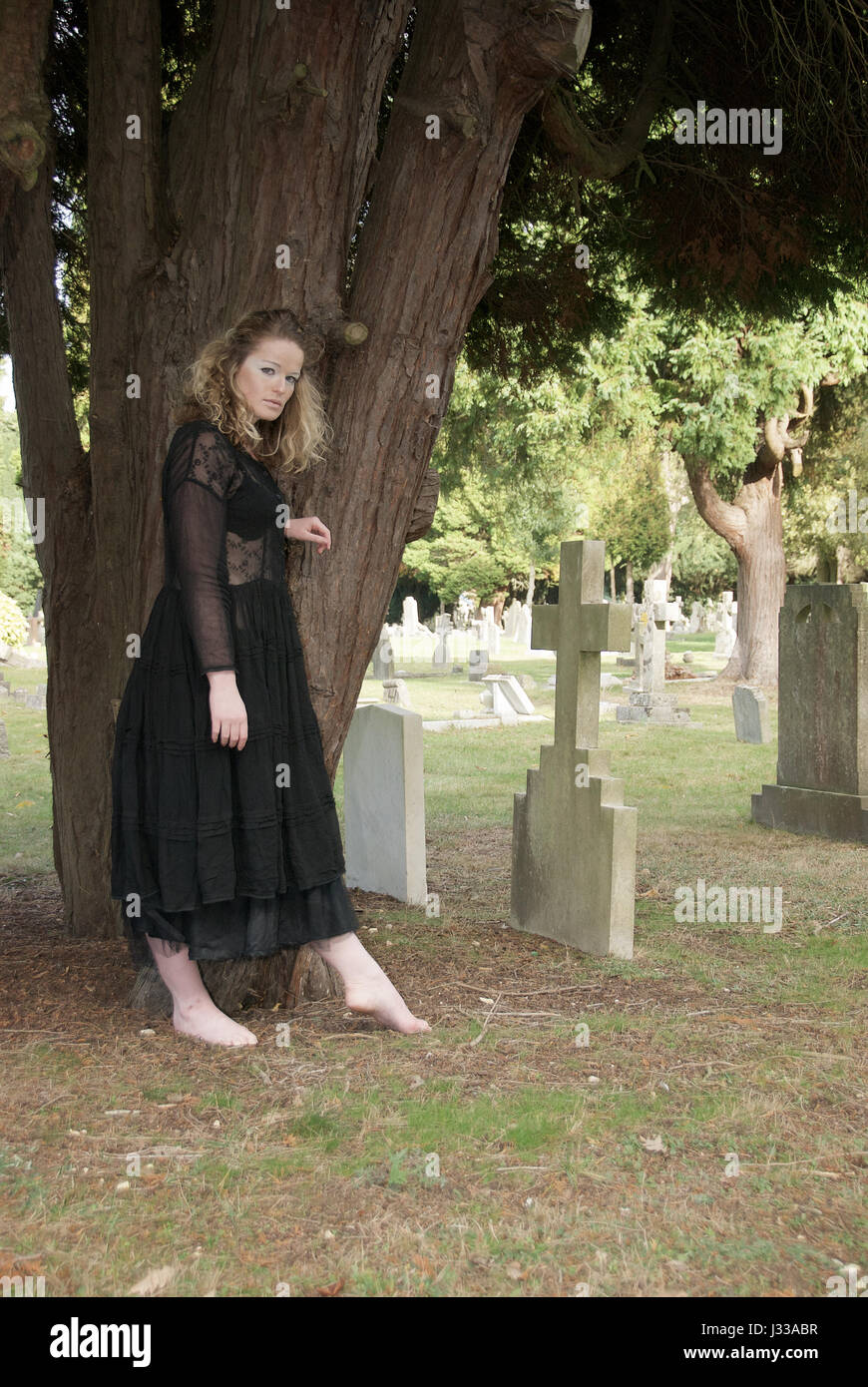 Beautiful blonde girl wearing a black dress in a graveyard Stock Photo ...