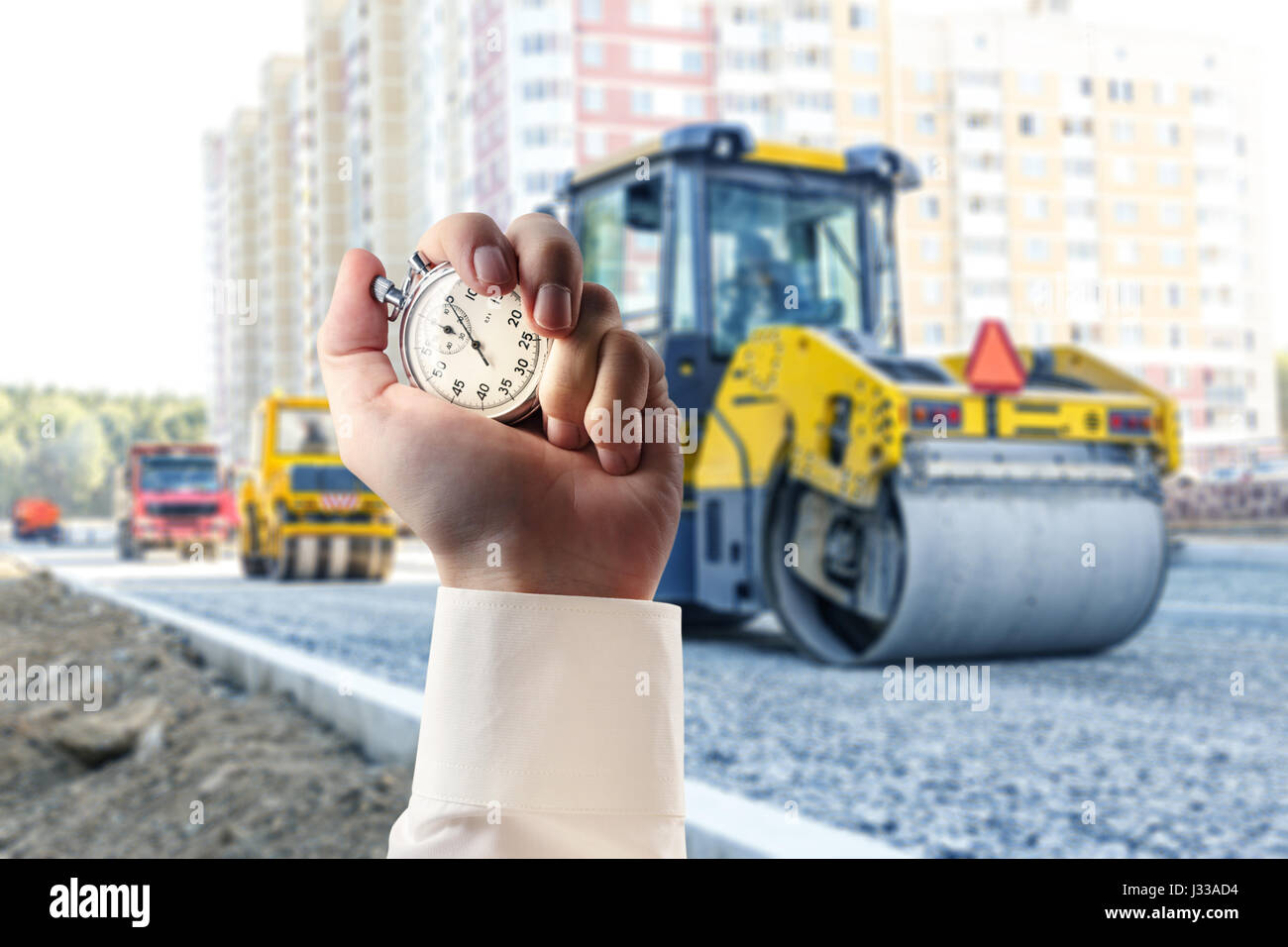 Road roller working and stopwatch in male hand Stock Photo - Alamy