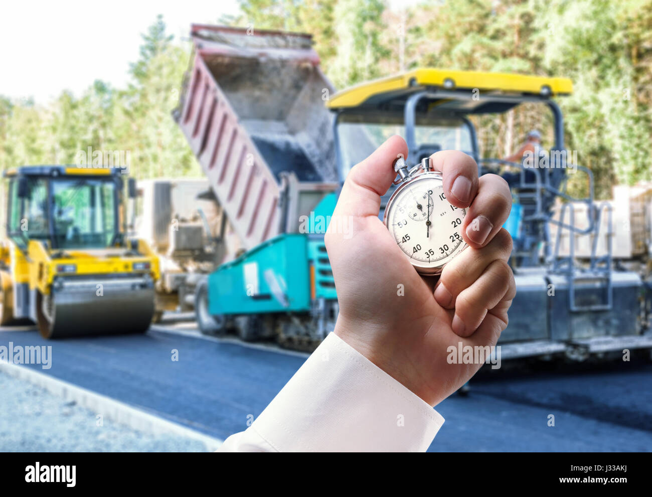 Road roller working and stopwatch in male hand Stock Photo - Alamy