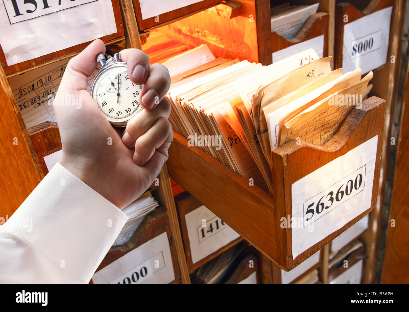 Paper documents stacked in archive and stopwatch in male hand Stock ...