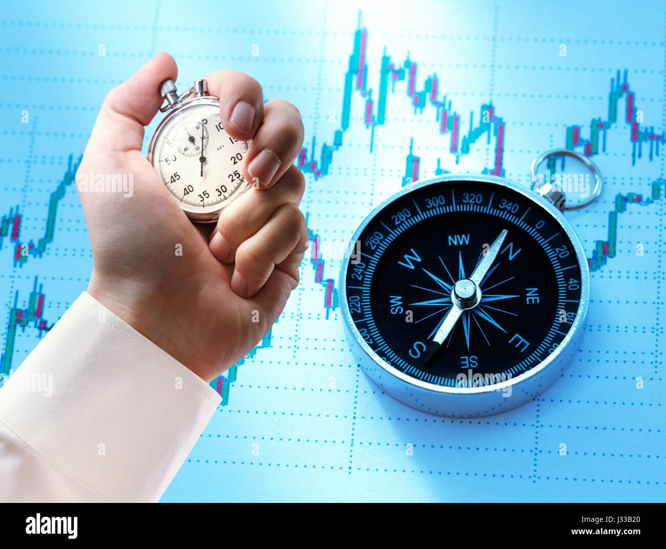 Candlestick chart graphic, compass and stopwatch in male hand Stock ...