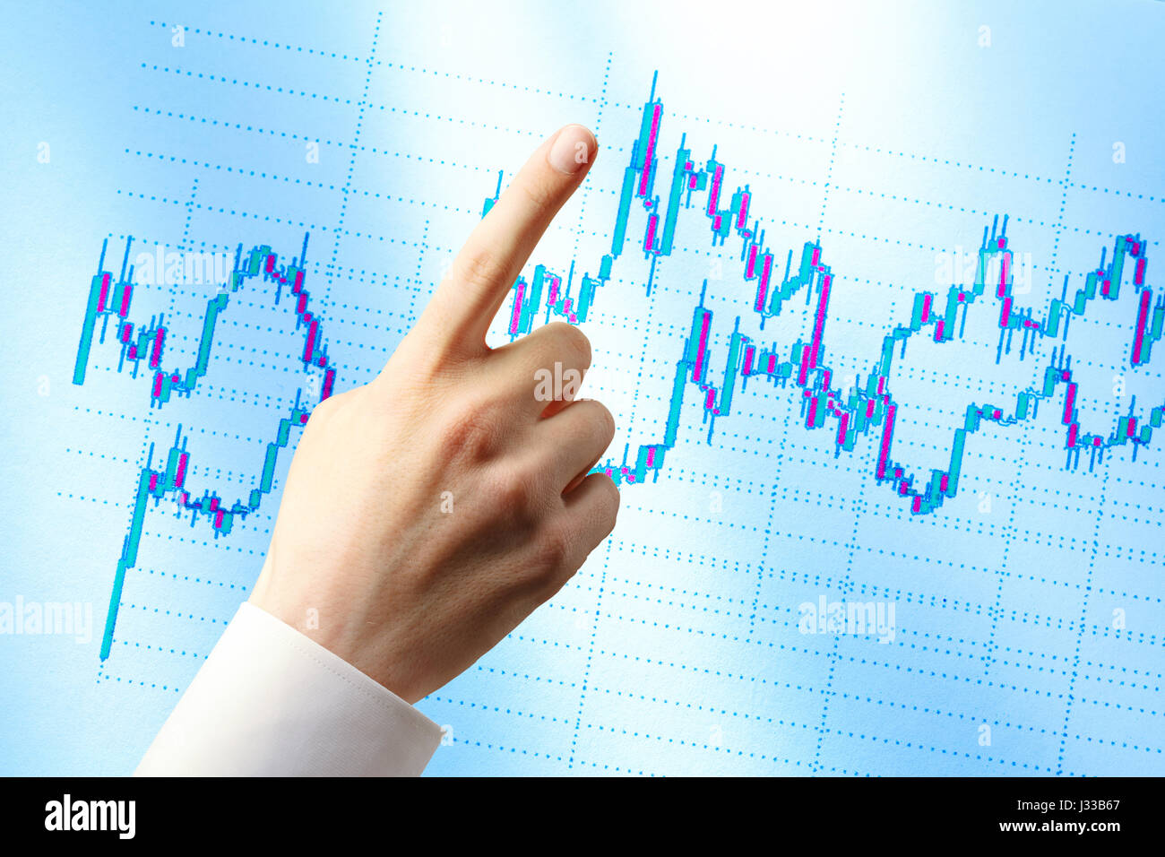 Candlestick chart and pointing forefinger of male hand Stock Photo - Alamy