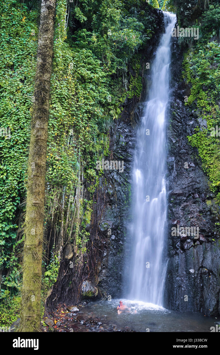 man bathing in a natural pool under a waterfall in the jungle, Dark ...