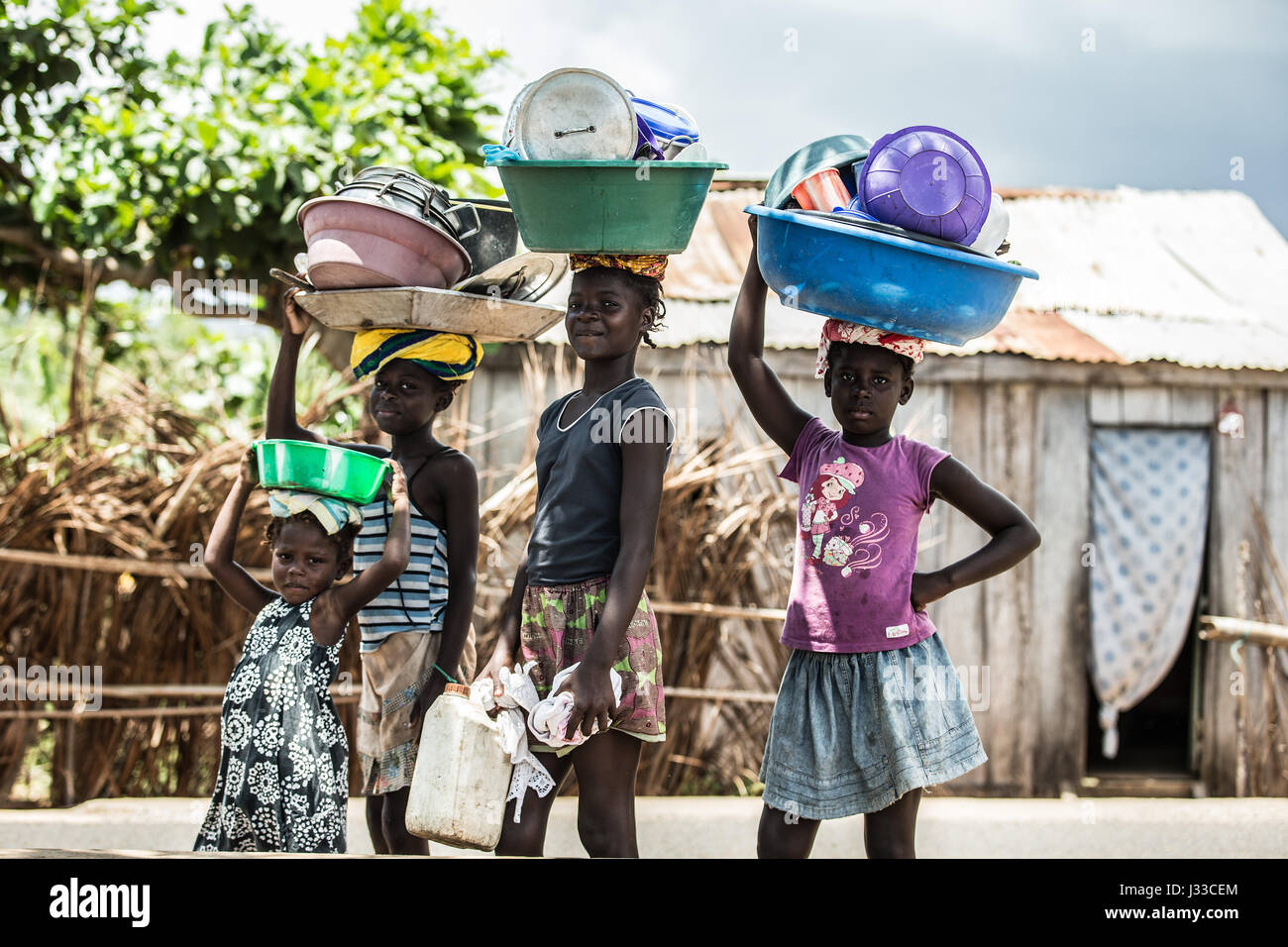 Little native children carrying their dishes in bowls on their heads ...