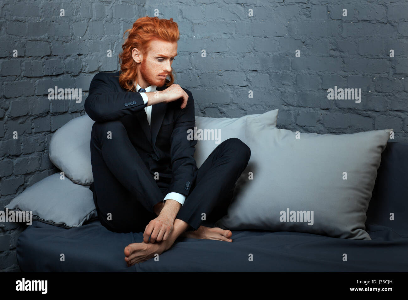 Metrosexual man with red hair and a beard sitting on a couch Stock ...