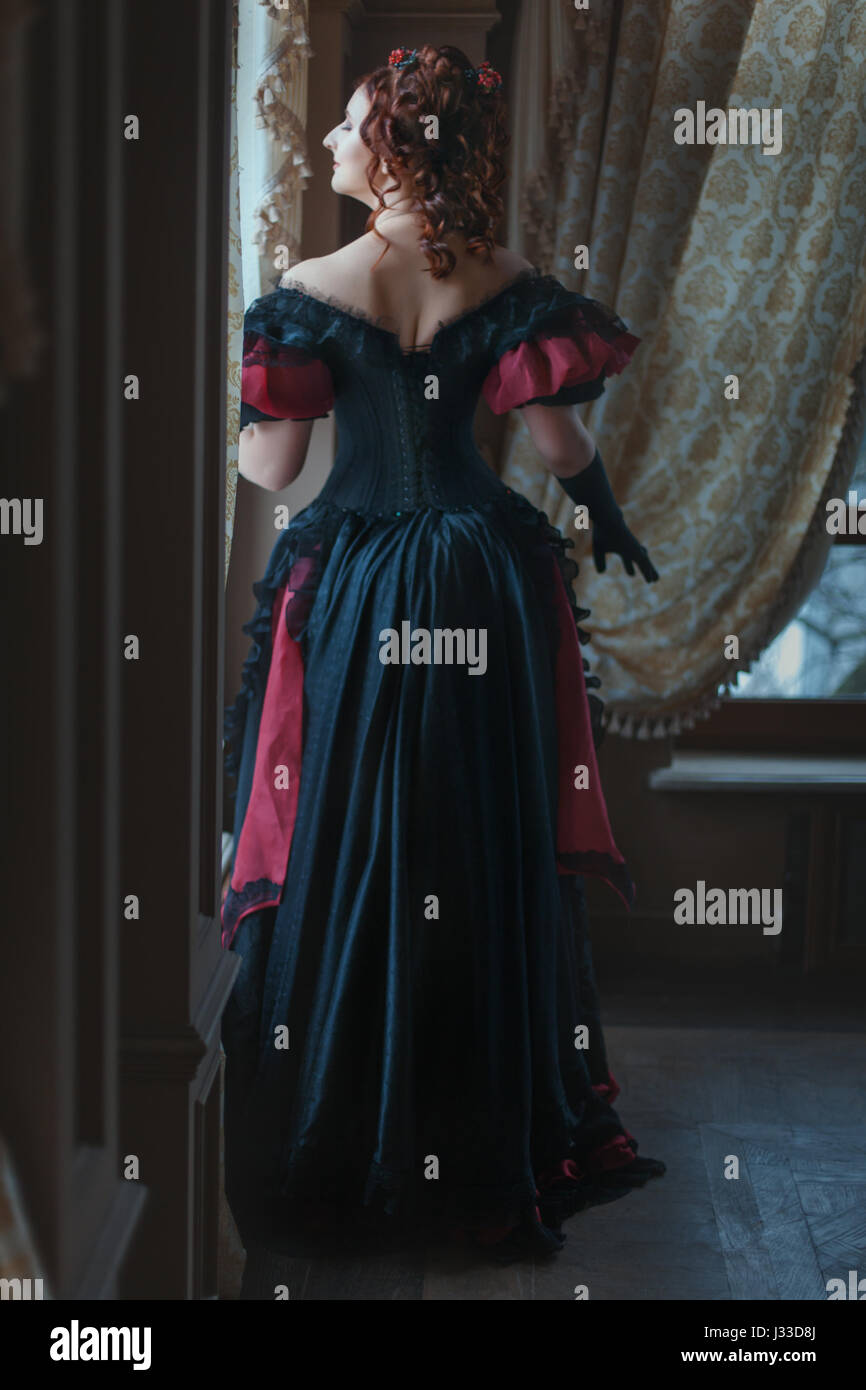 Woman in Victorian dress standing back at the window Stock Photo - Alamy
