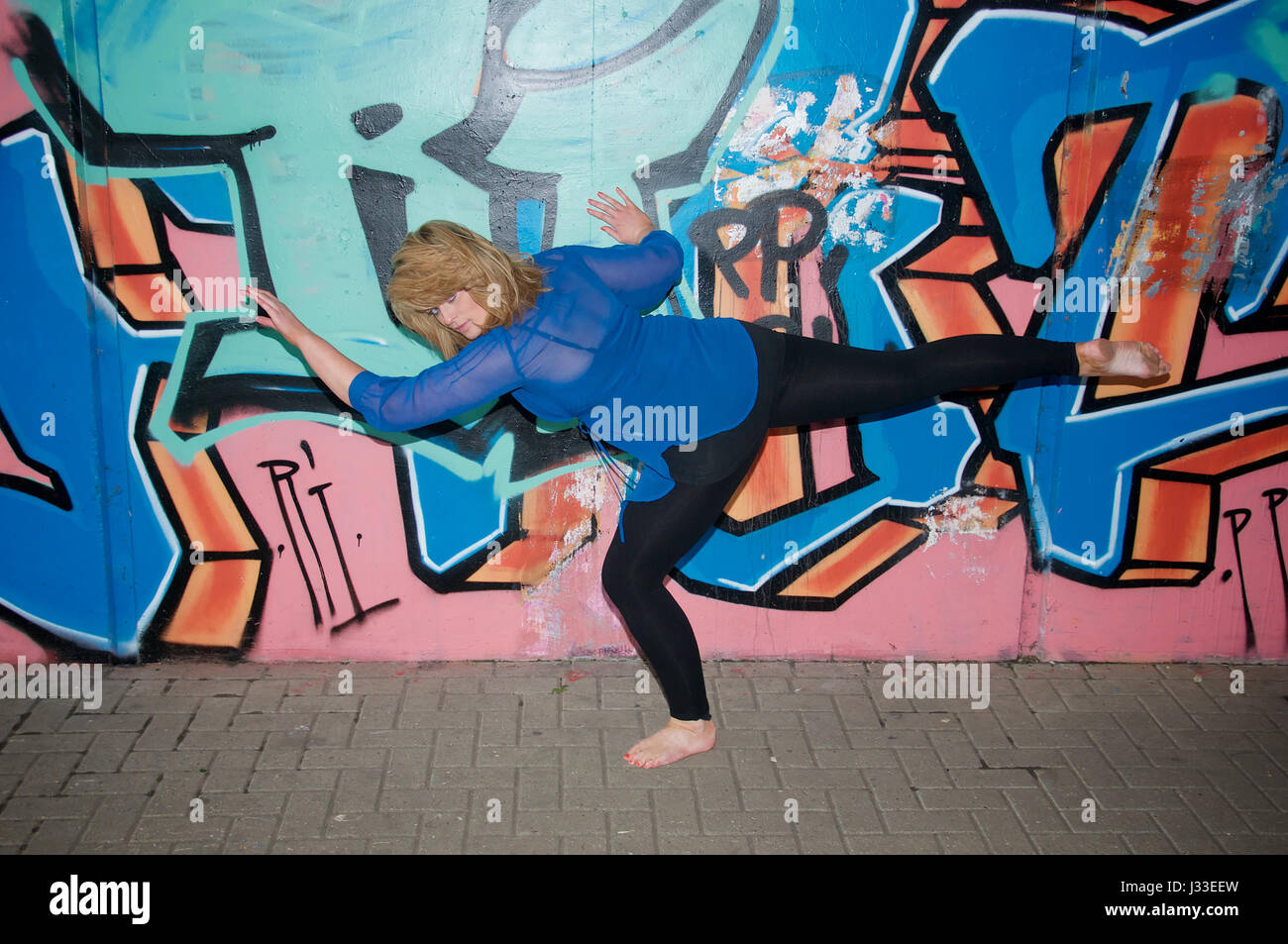 Beautiful blonde girl dancer against a graffiti covered wall wearing ...