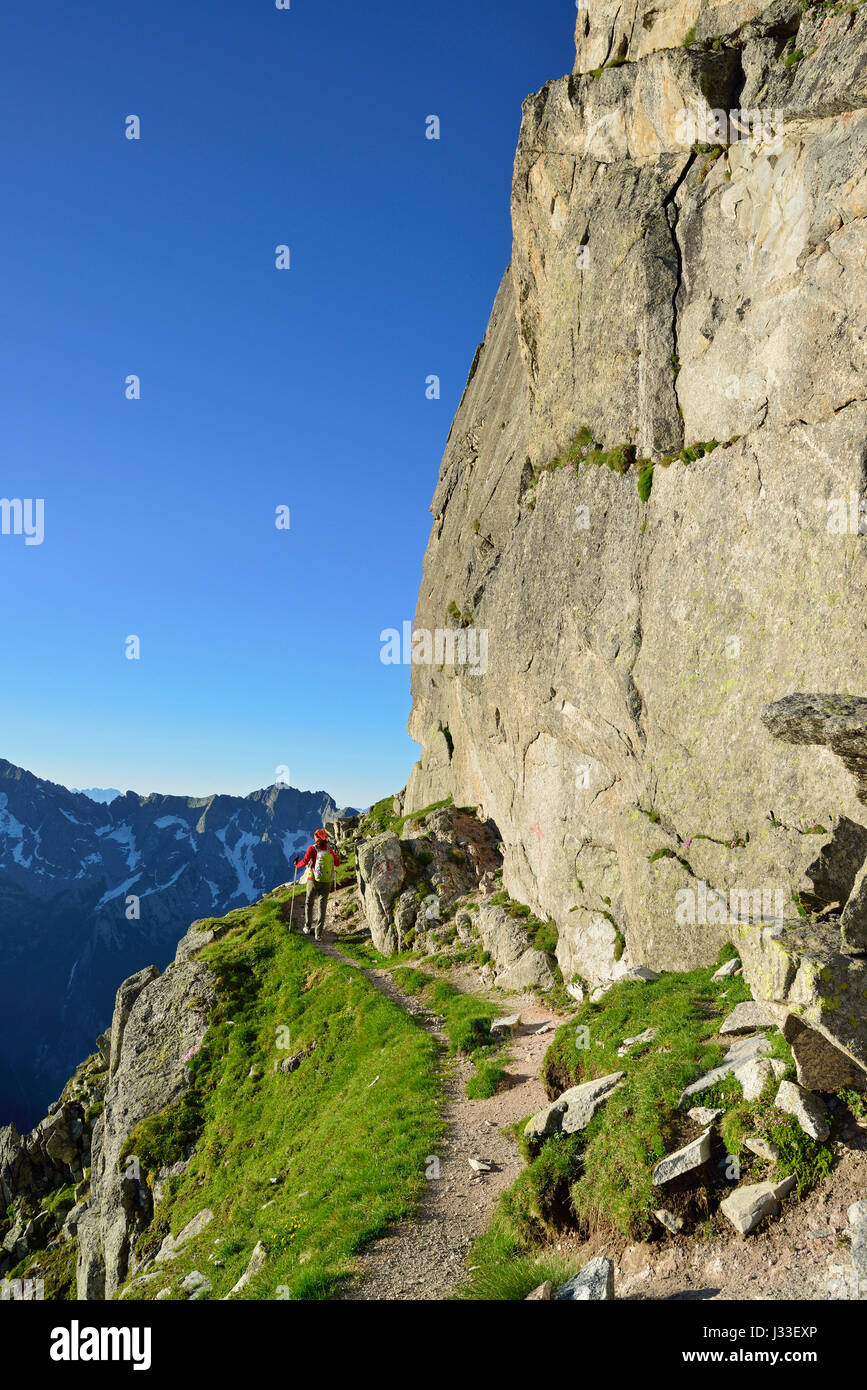 Woman hiking beneath rockface, Sentiero Roma, Bergell range, Lombardy ...