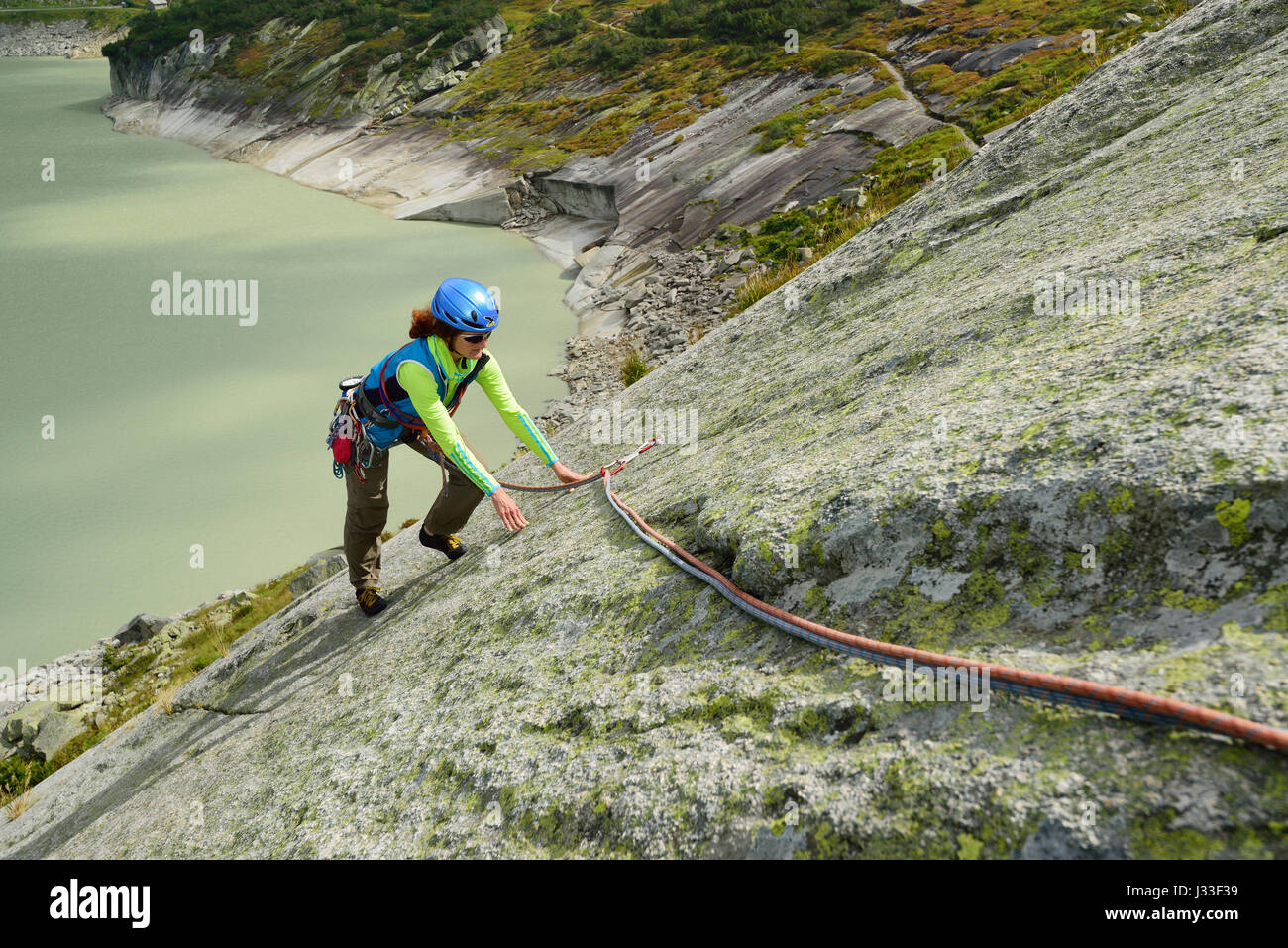 Woman climbing on granite slab, lake in background, Raeterichsboden ...