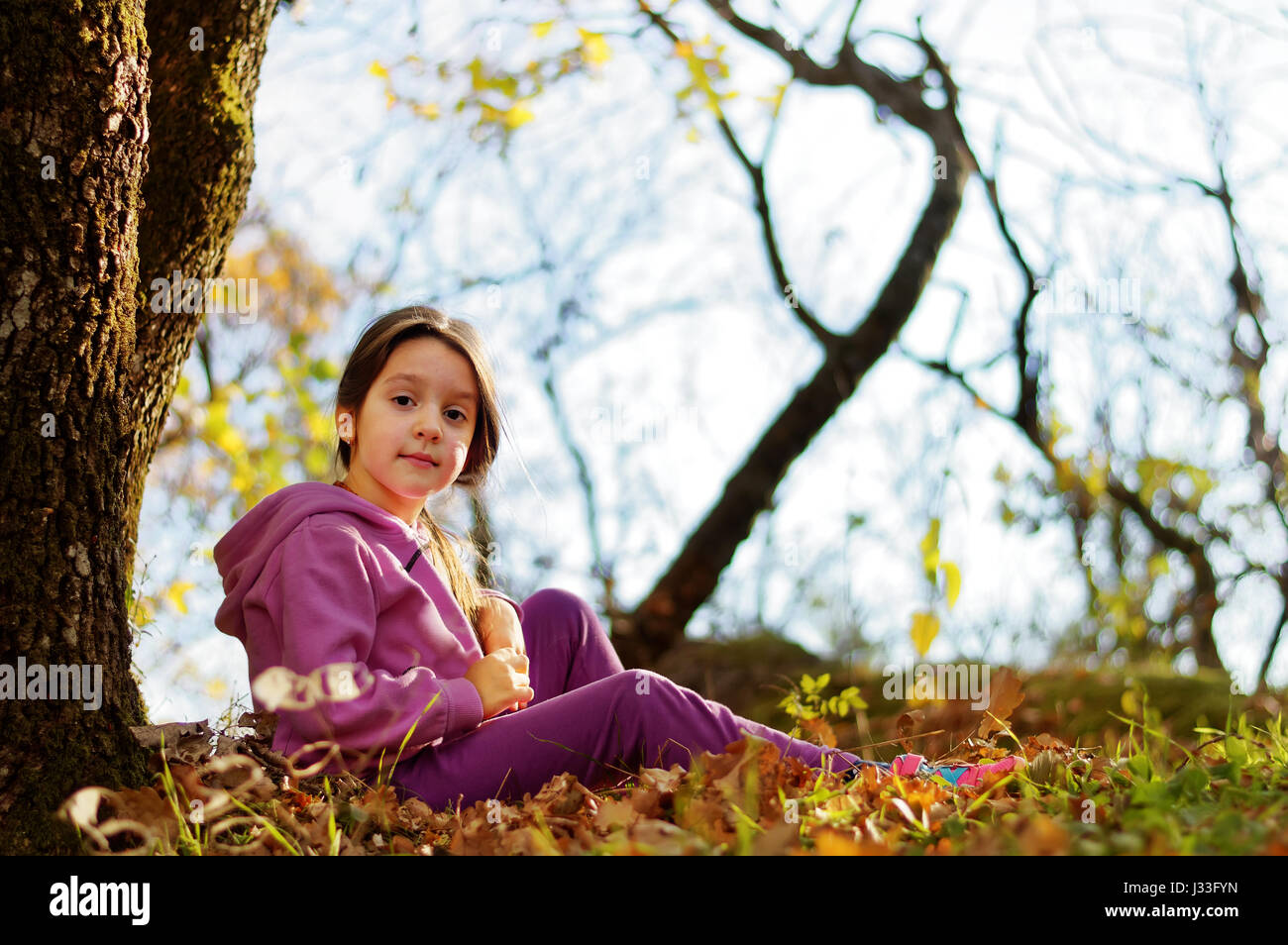 girl sitting on the carpet of leaves and enjoys a beautiful autumn day ...