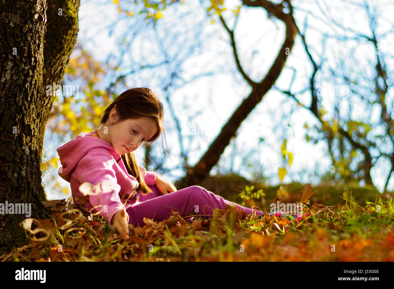 girl sitting on the carpet of leaves and enjoys a beautiful autumn day ...
