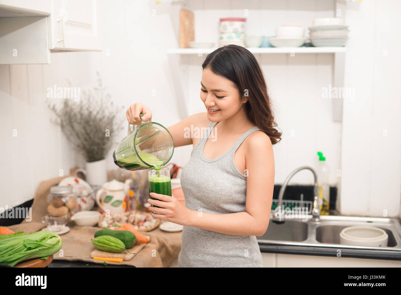 Smiling Asian Woman Making Smoothie With Fresh Vegetables In The