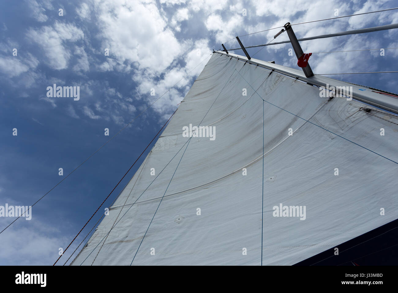 White main sail against blue sea with clouds Stock Photo - Alamy