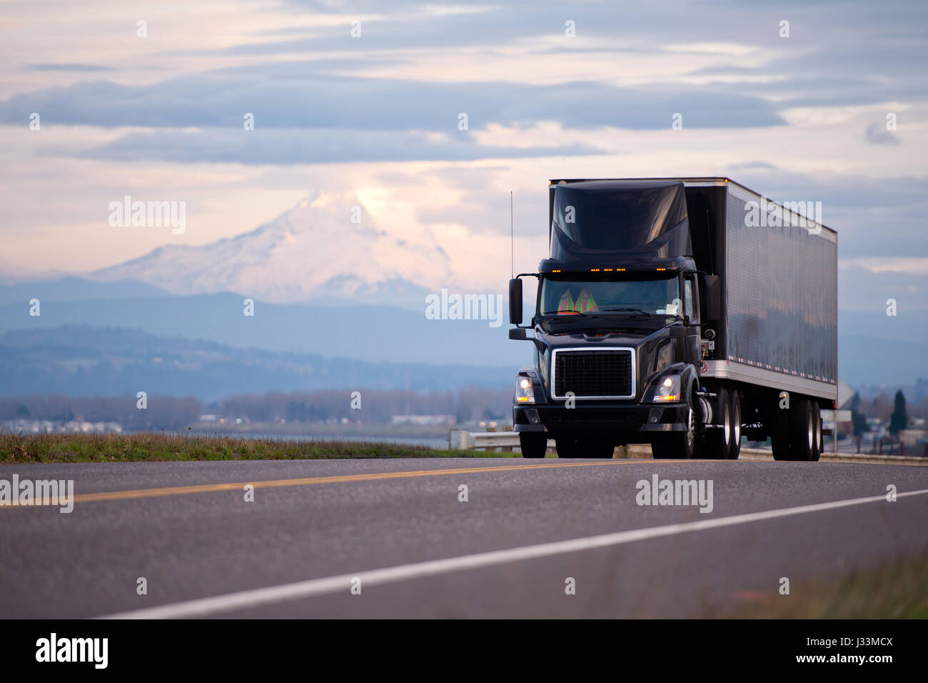 Stylish black modern powerful semi truck and trailer with a black roof ...