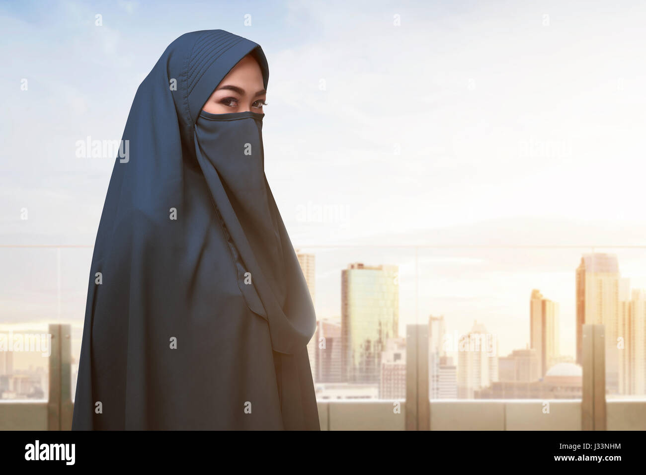 Religious asian muslim woman with covered face standing against ...