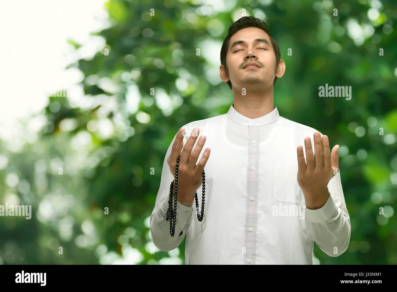 Young asian muslim man praying with prayer beads in the outdoor Stock ...