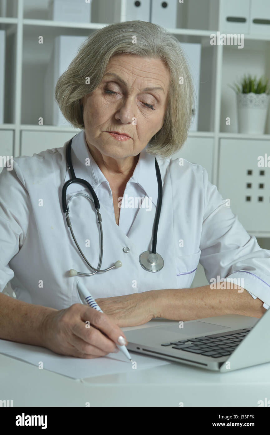 Old doctor with a laptop working Stock Photo - Alamy
