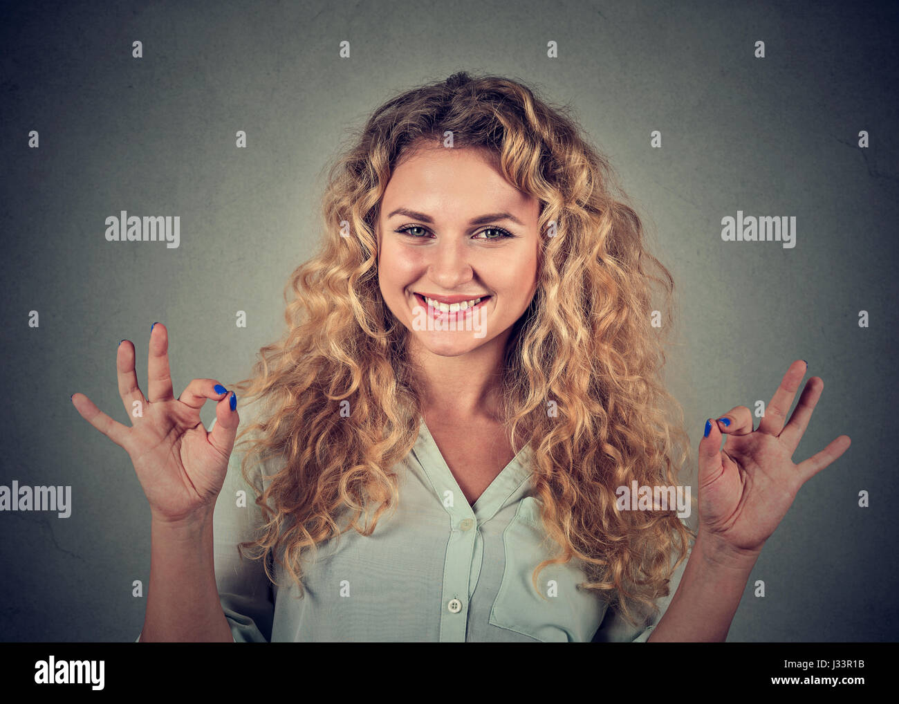 Beautiful young woman showing Ok sign isolated on gray wall background ...