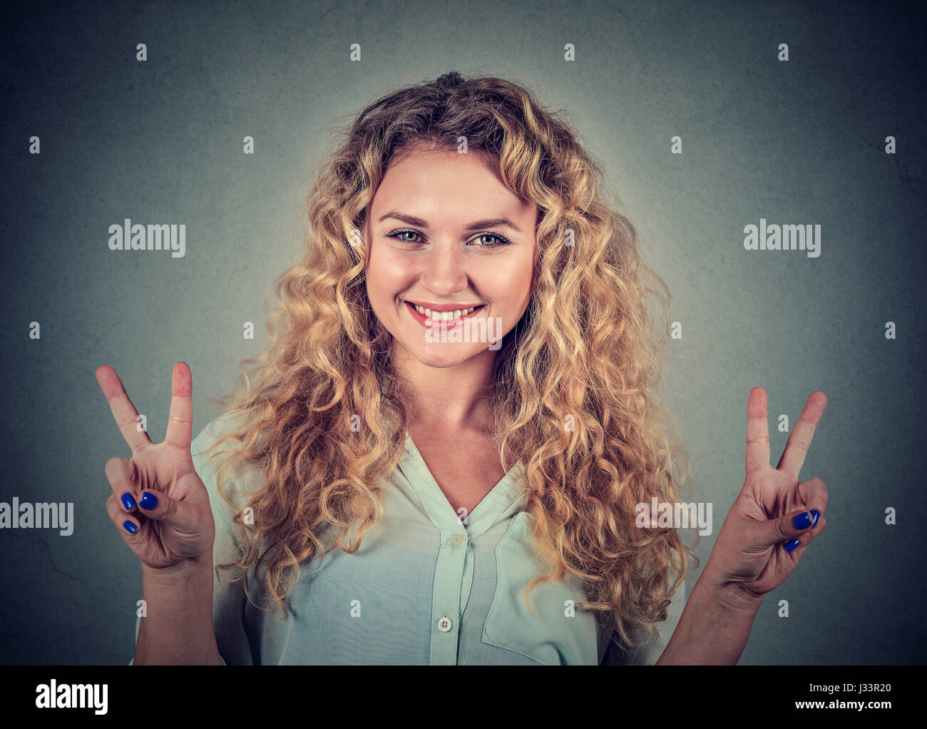 Happy teenage girl showing victory or peace sign isolated on gray ...