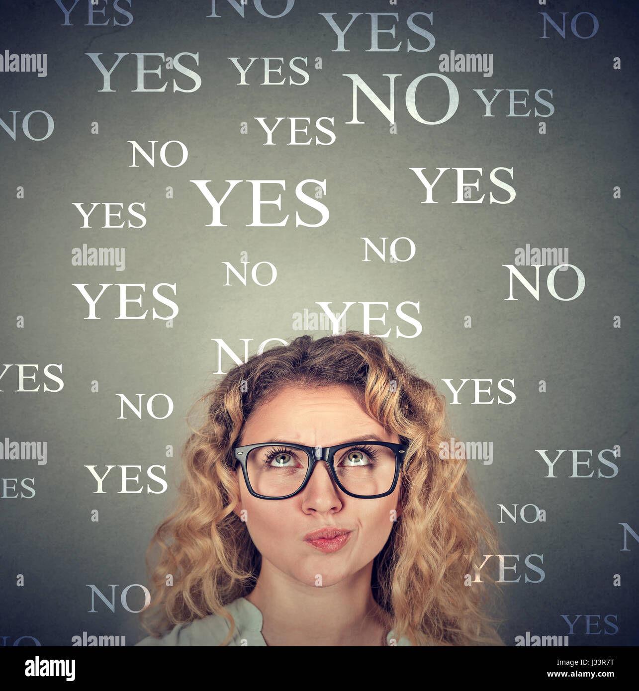 Thinking skeptical young woman in glasses with yes or no choice looking ...