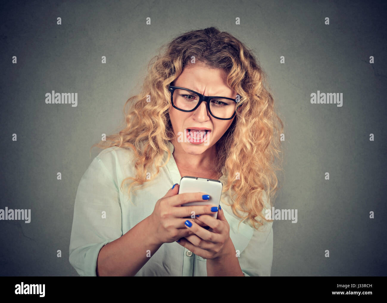 Portrait of stressed office young woman holding cellphone in hands ...