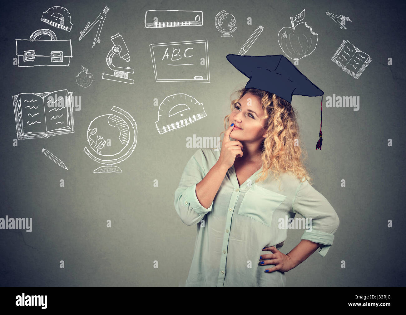 Young beautiful business woman with graduation hat looking up thinking ...