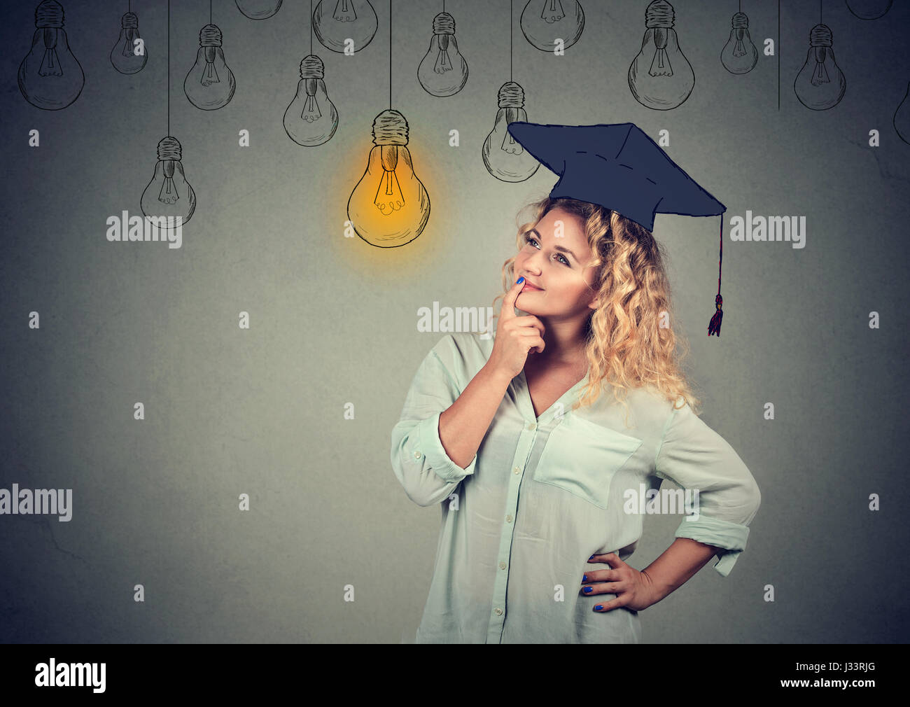 Thoughtful graduate student girl young woman in cap gown looking up at ...