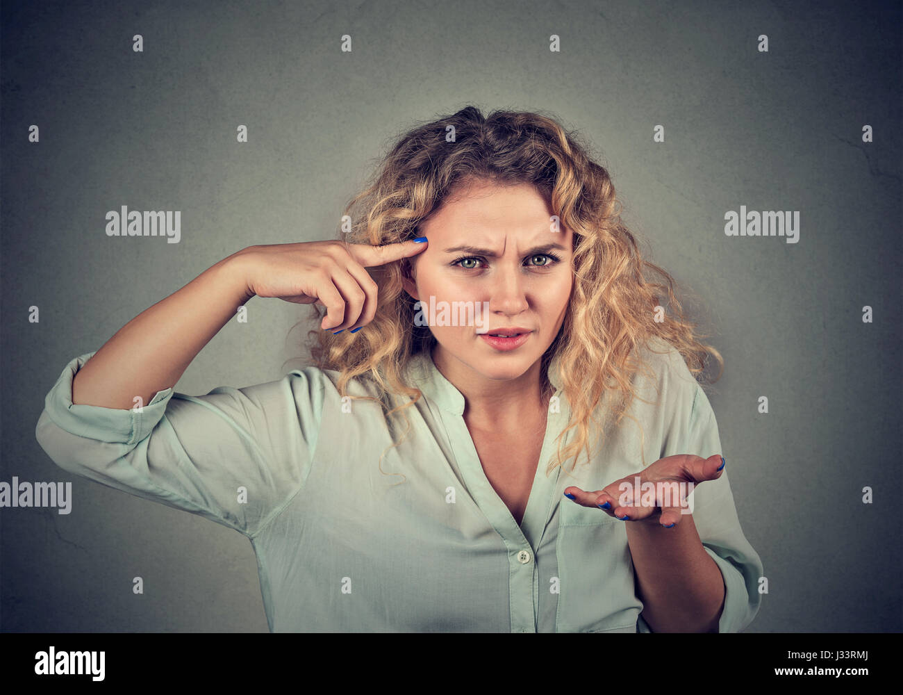 angry mad young woman gesturing with finger against temple are you ...
