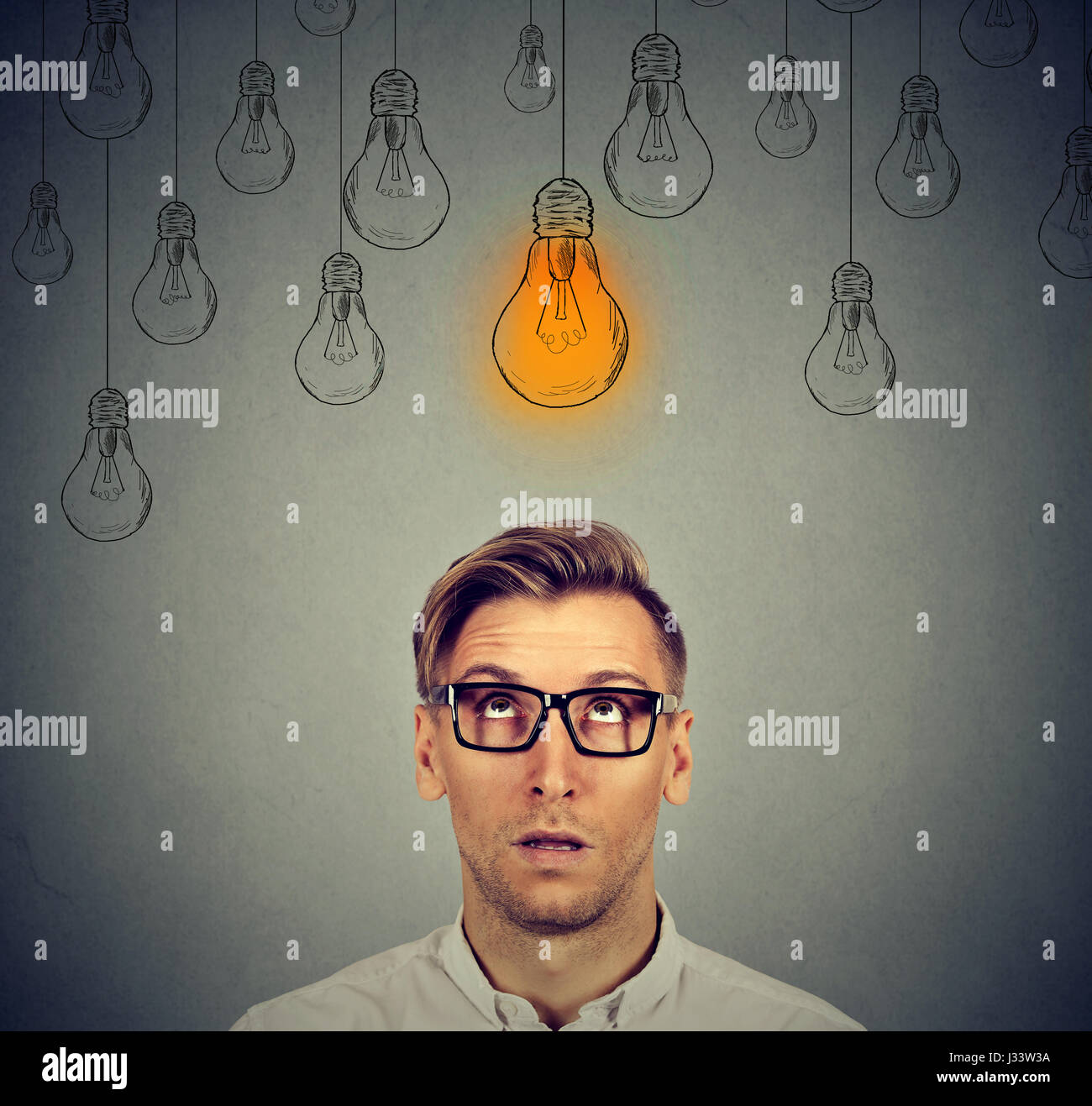 Thoughtful man in glasses looking up with light idea bulb sign above ...