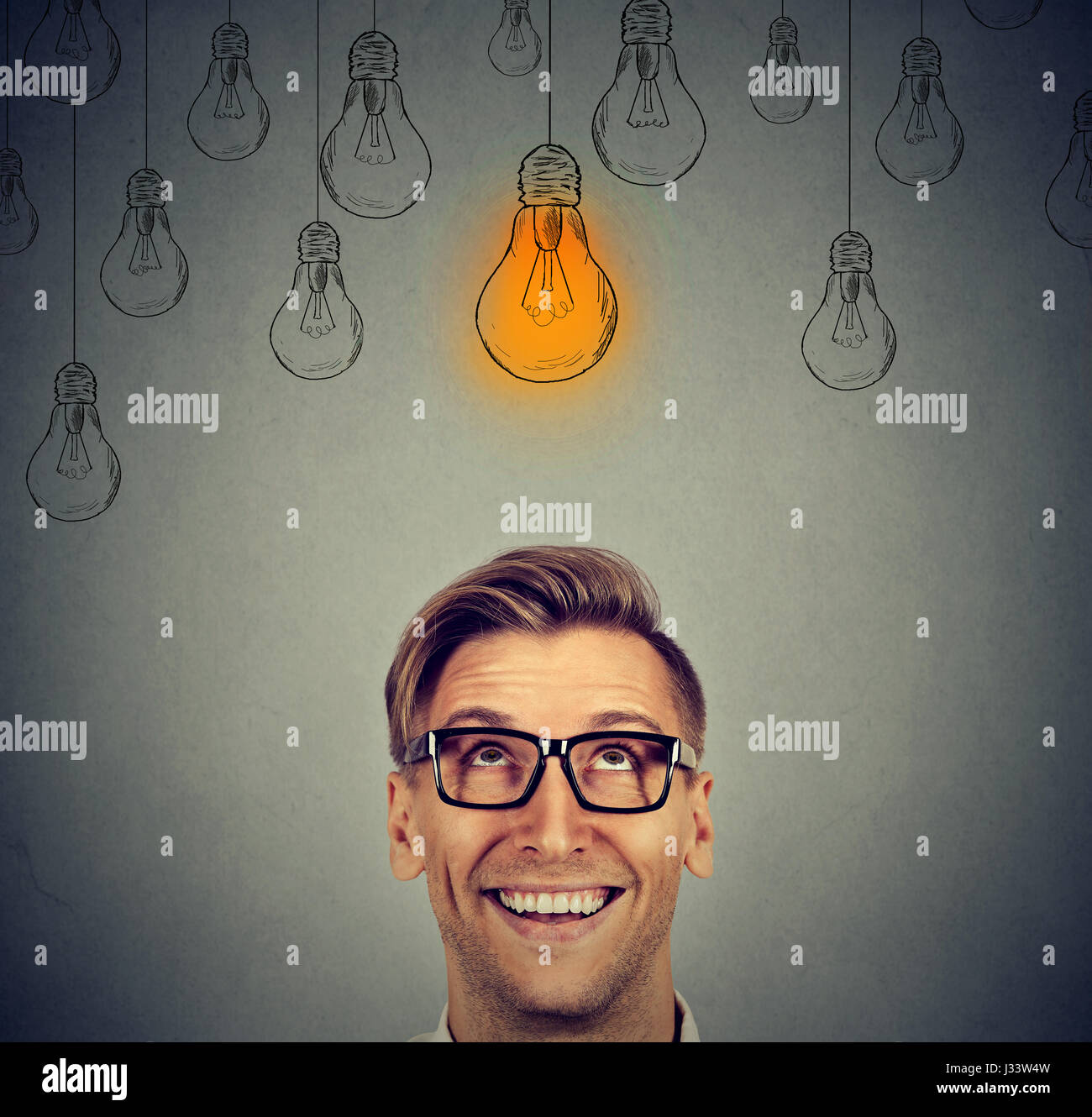 Portrait happy handsome man in glasses looking up at bright idea light ...