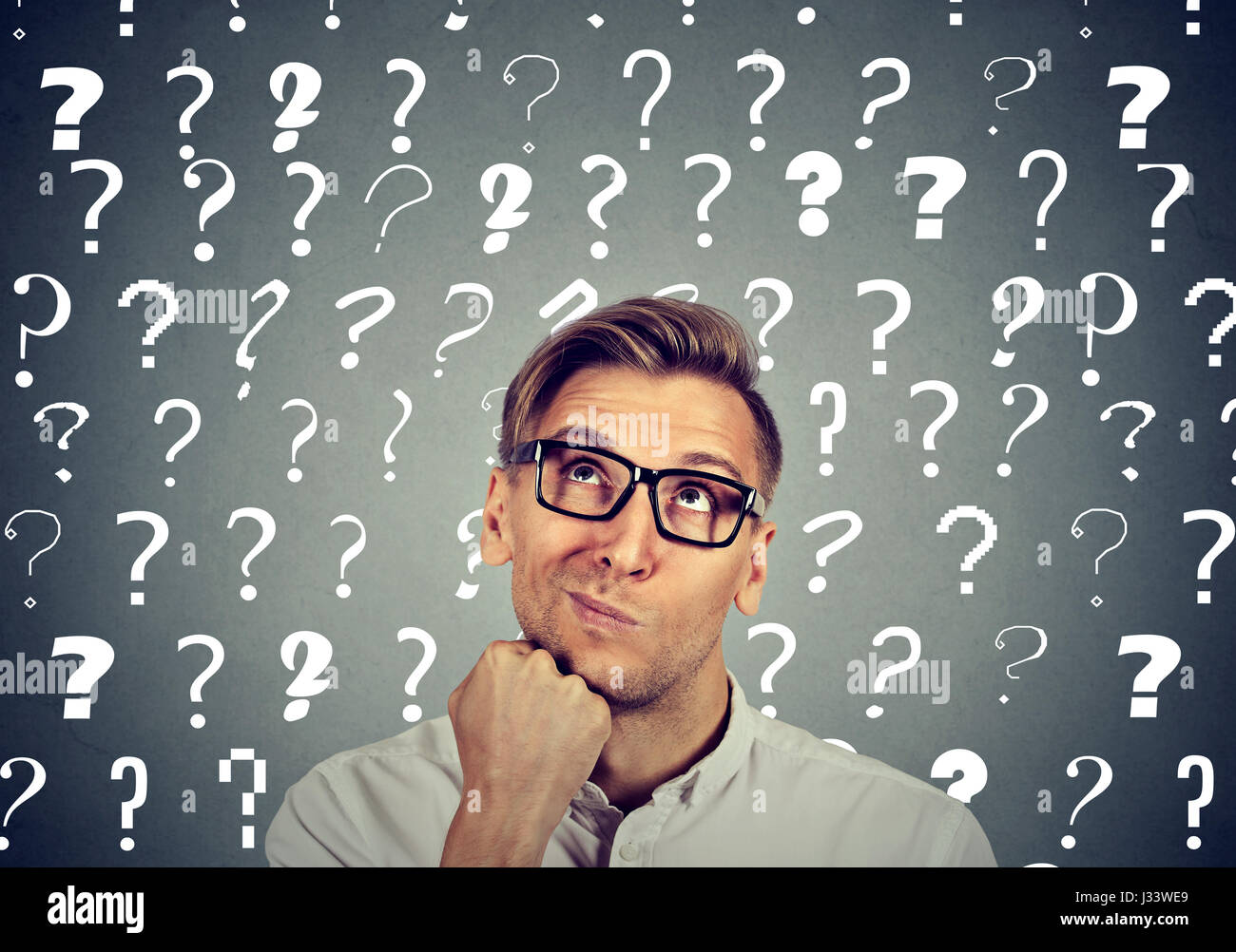 Thoughtful confused handsome man in glasses has too many questions and ...