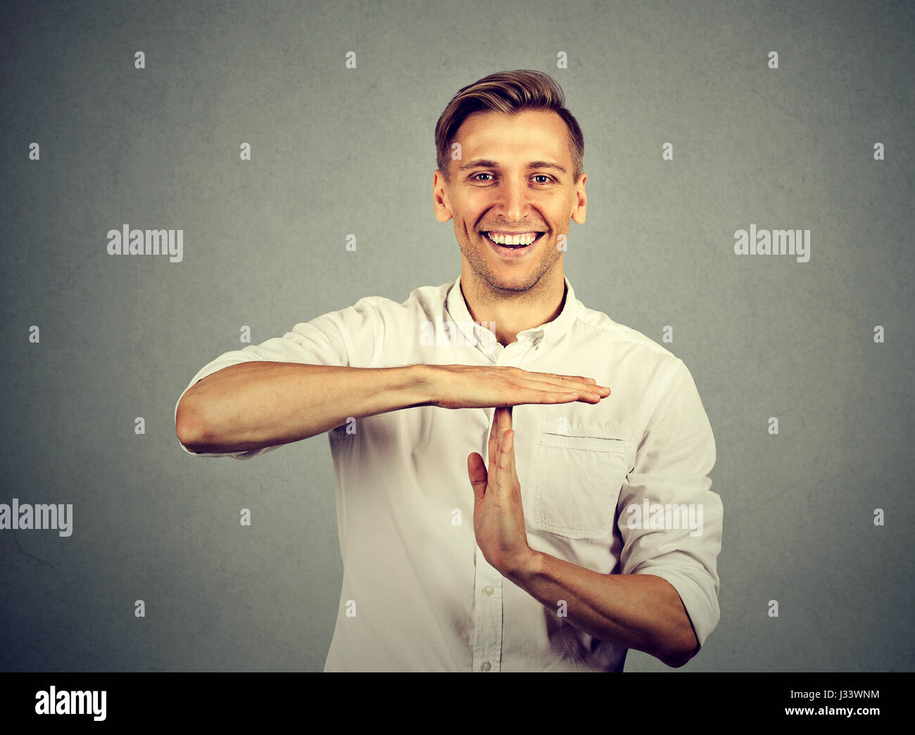 happy businessman giving time out hand gesture isolated on gray wall ...