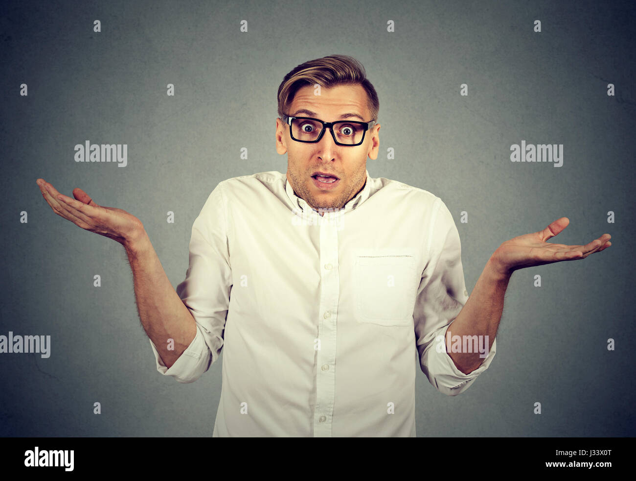 Closeup portrait young man shrugging shoulders who cares so what I don ...